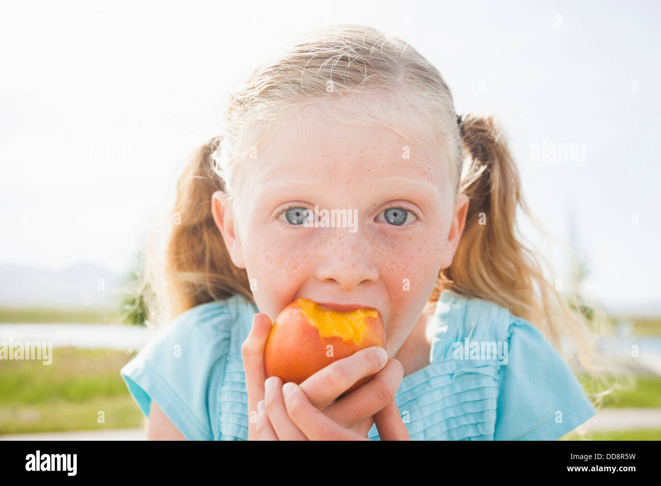 Caucasian girl eating fruit outdoors Stock Photo - Alamy