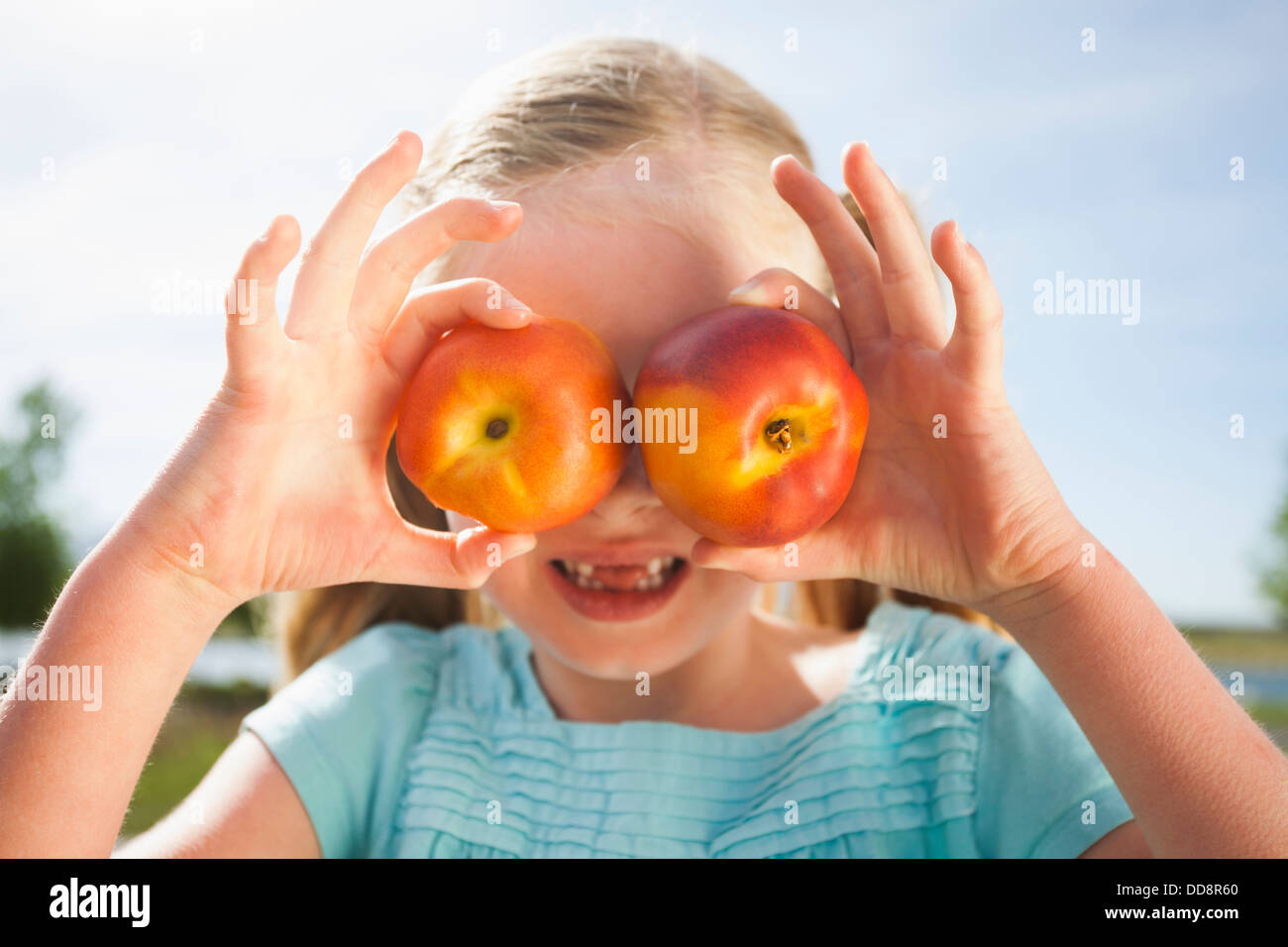 Caucasian girl holding fruit over eyes Stock Photo - Alamy