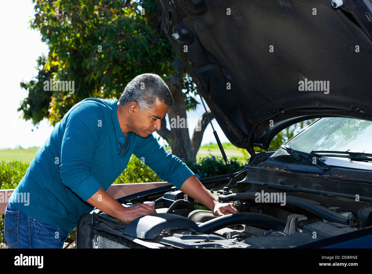 Mixed race man working on car engine Stock Photo - Alamy