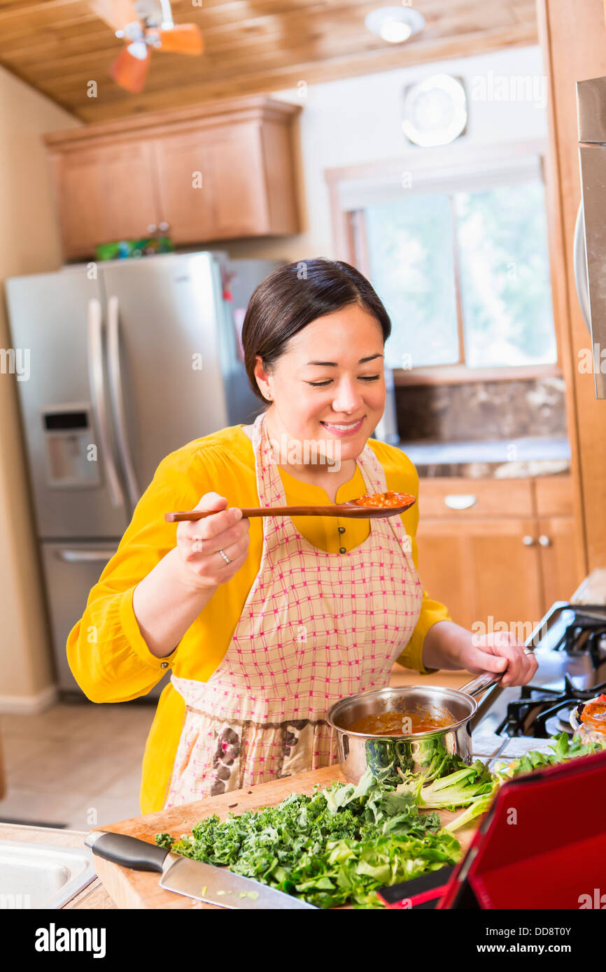 Mixed race woman cooking in kitchen Stock Photo - Alamy
