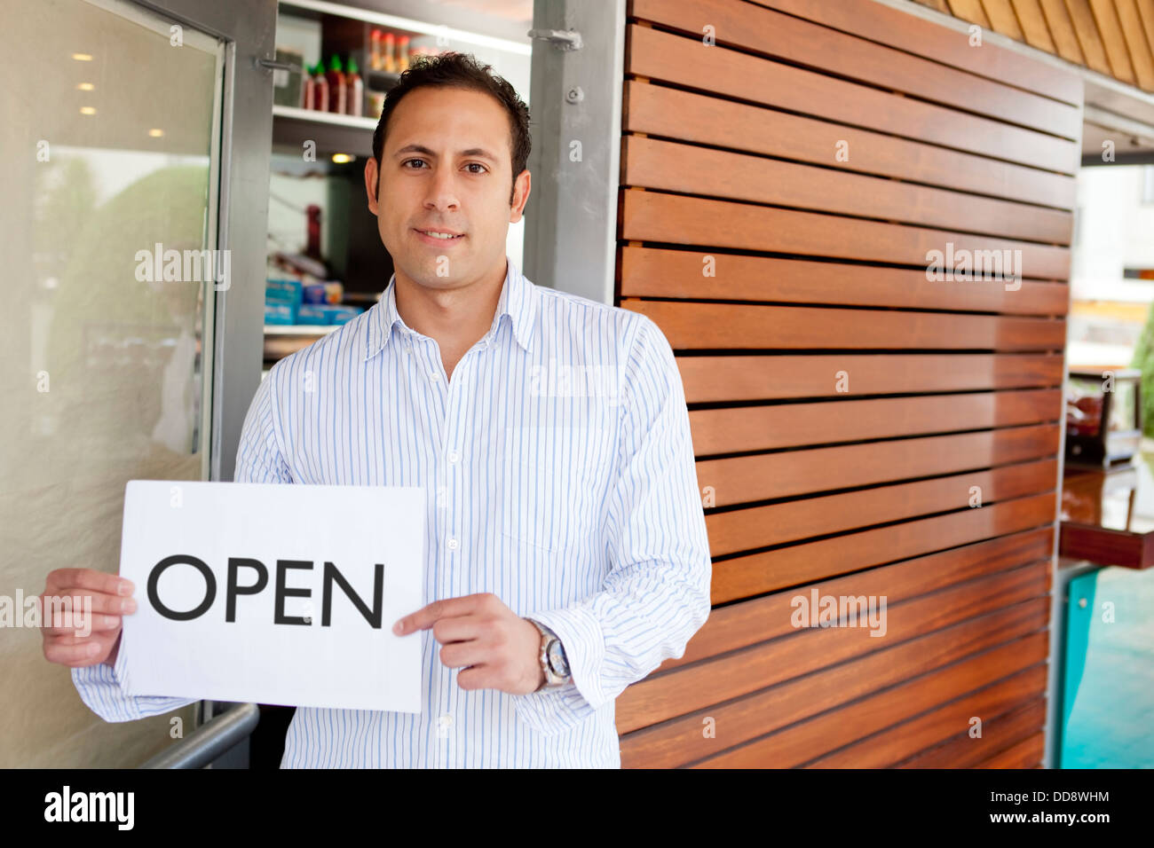 Hispanic man holding 'open' sign in door Stock Photo - Alamy