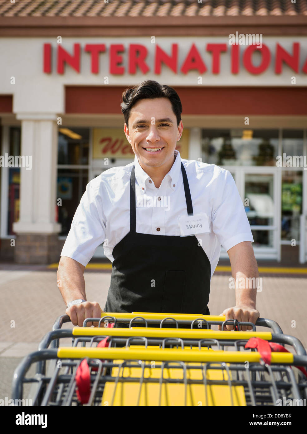 Hispanic worker pushing carts outside grocery store Stock Photo - Alamy