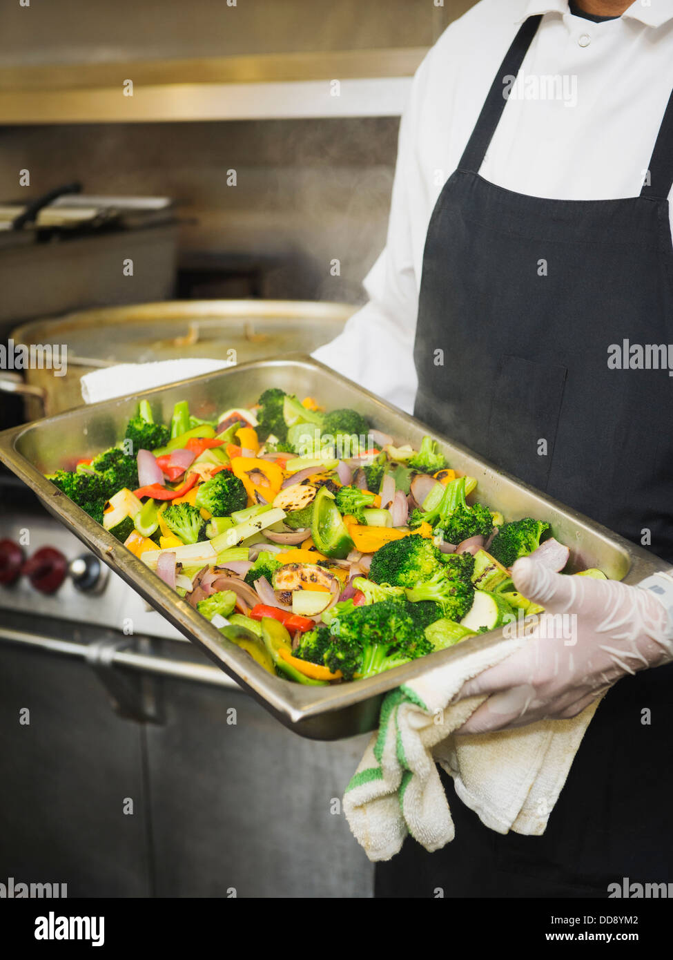 Hispanic chef with tray of vegetables in kitchen Stock Photo - Alamy