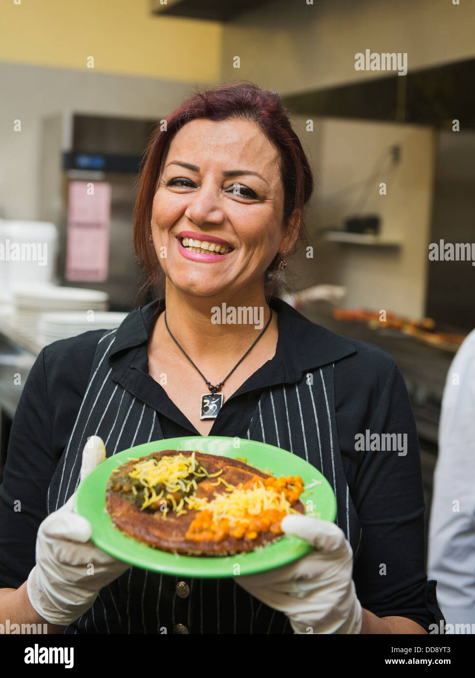 Mixed race chef holding plate of food in kitchen Stock Photo - Alamy
