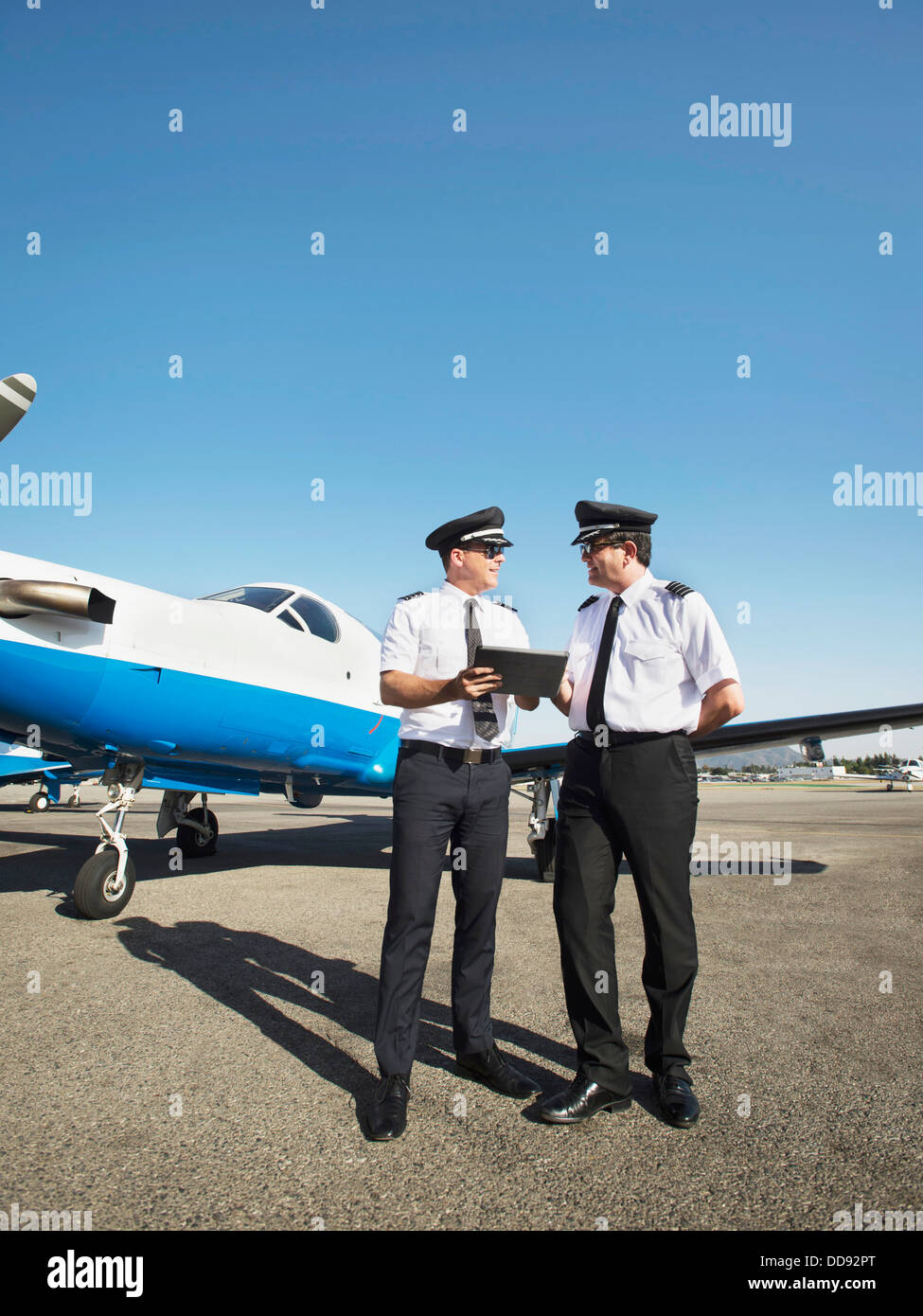 Caucasian pilots using digital tablet on runway Stock Photo - Alamy