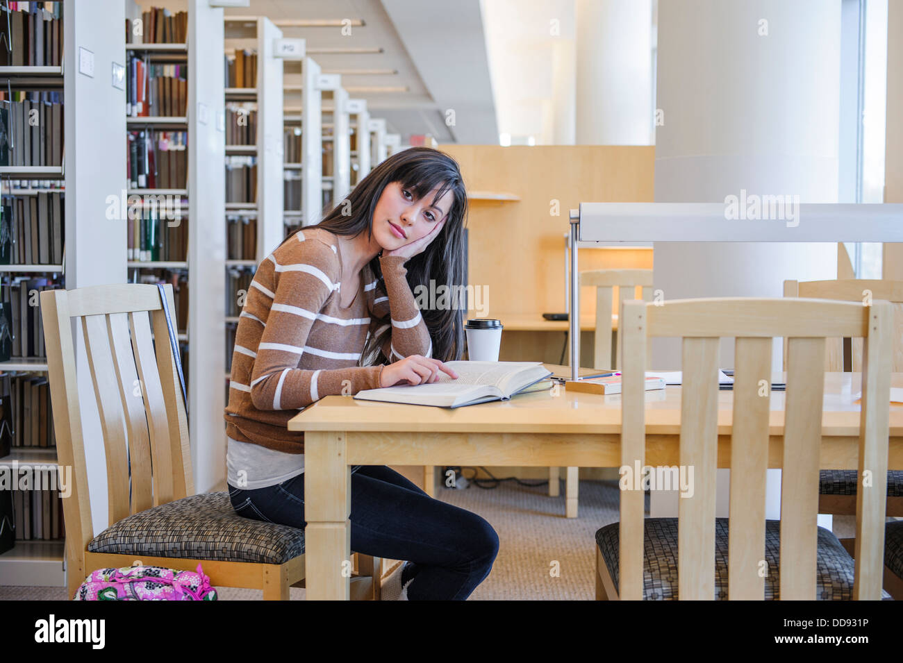 Student working at desk in library Stock Photo - Alamy