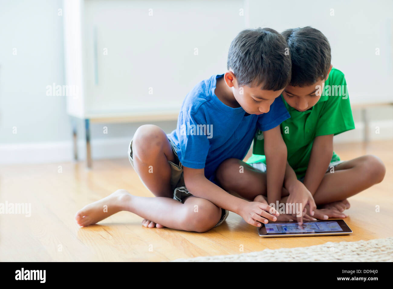Boys using digital tablet on floor Stock Photo - Alamy