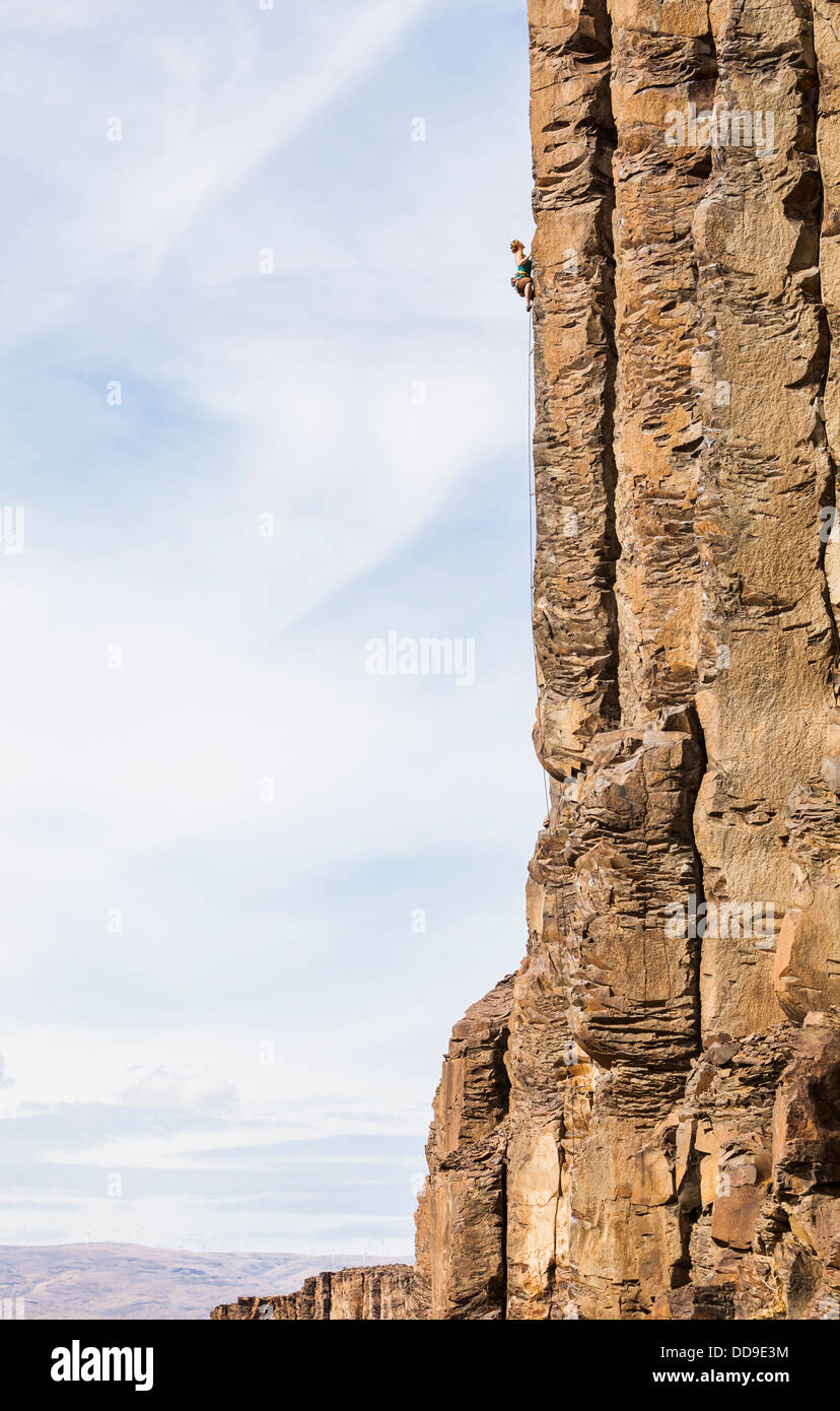 A woman climbing a basalt rock cliff in central Washington State, USA ...