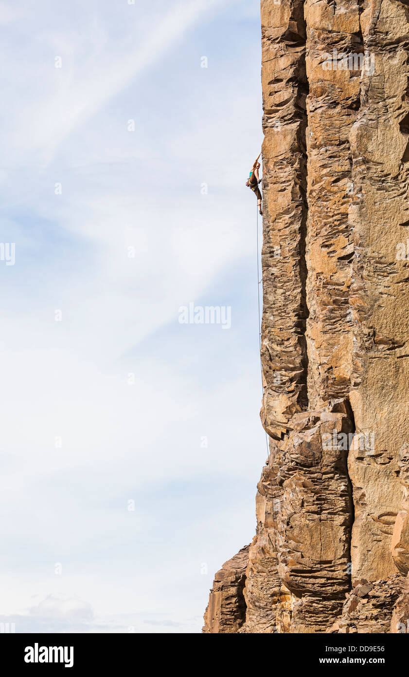 A woman climbing a basalt rock cliff in central Washington State, USA ...