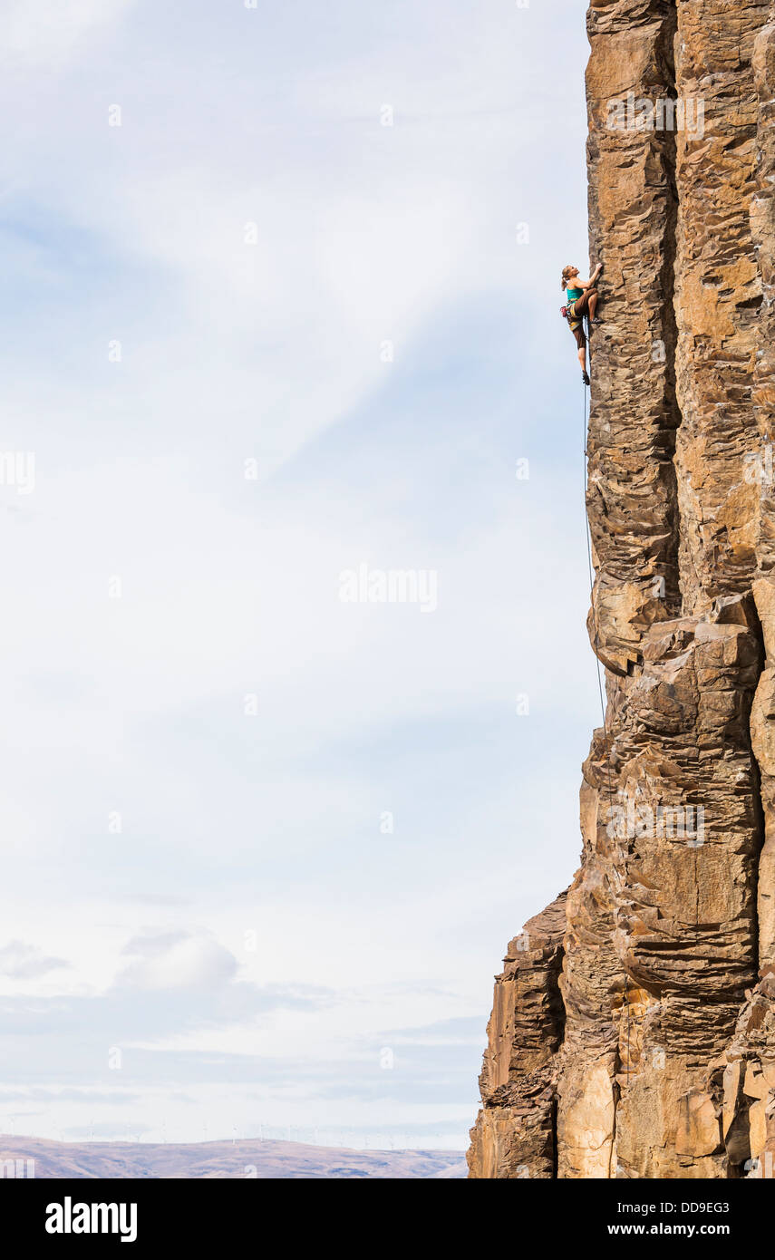 A woman climbing a basalt rock cliff in central Washington State, USA ...