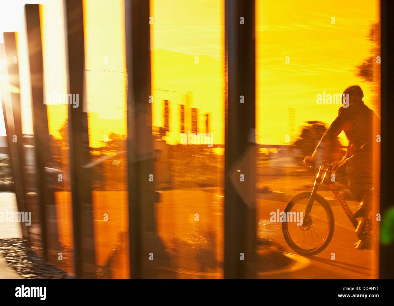 Man riding push bike behind orange glass Stock Photo - Alamy
