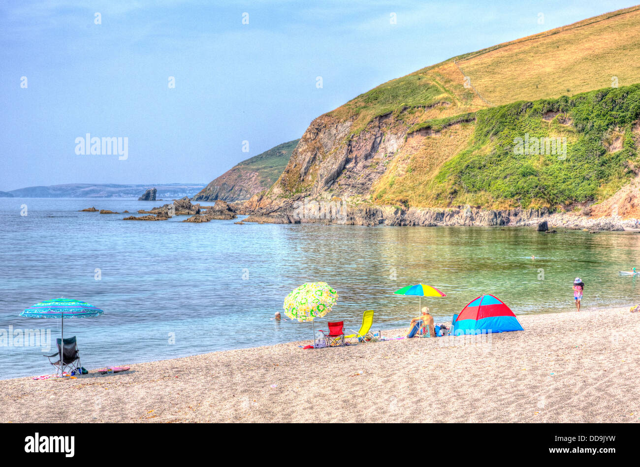Colourful umbrellas on beach with blue sea and coast in Cornwall ...