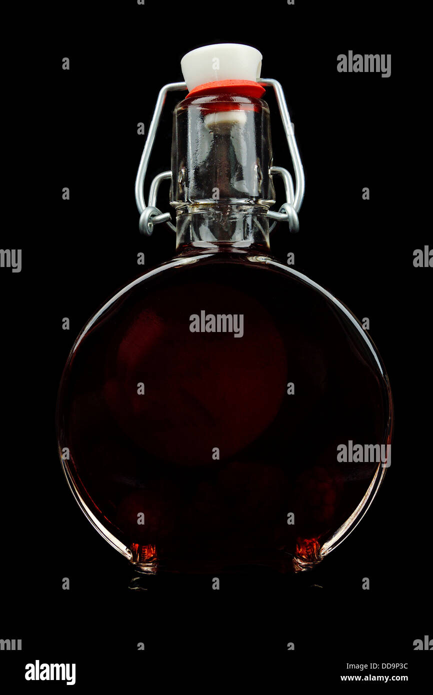 Bottle with raspberry liquor on black background Stock Photo - Alamy