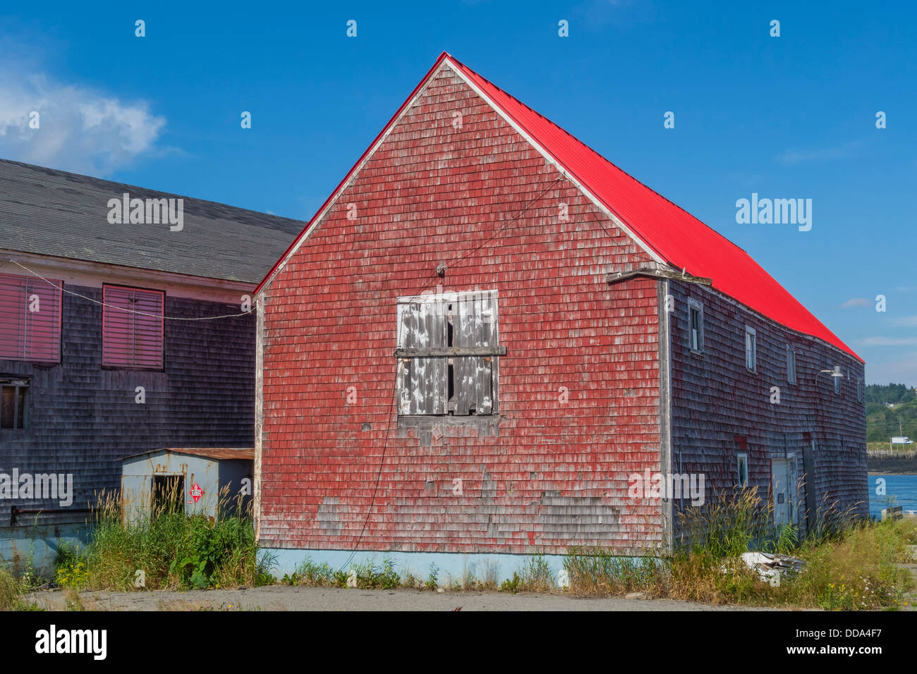 A red wooden shingled fishing building with a red metal roof by the ...
