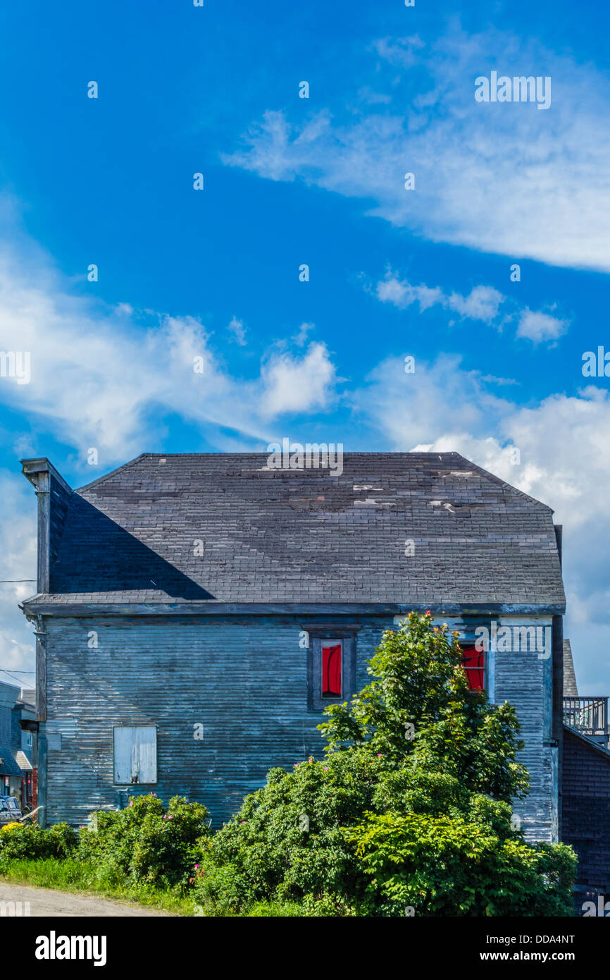 A red reflection of a red metal roof in a window of a deserted, run ...