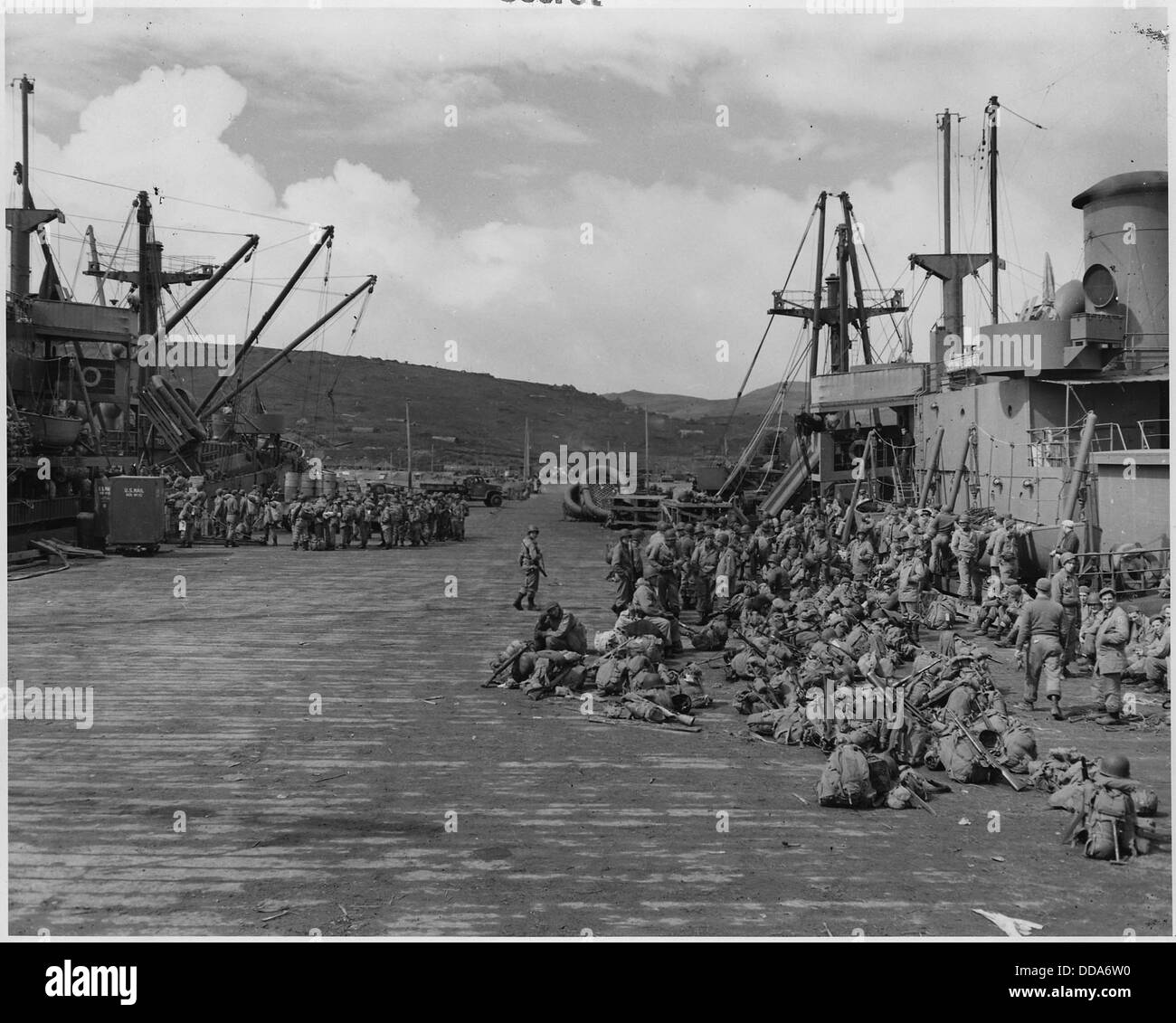 This photograph shows troops loading onto transport ships for the ...