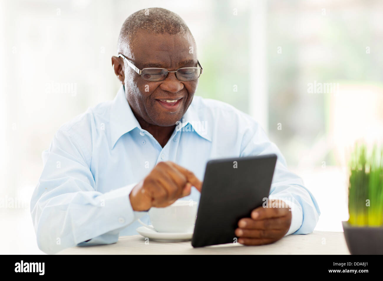 cheerful senior African American man using tablet computer at home ...