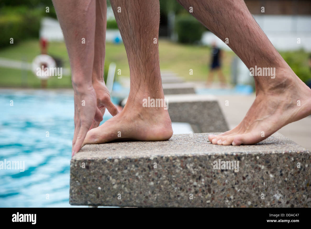 Man standing on starting block at public swimming pool ready to jump ...