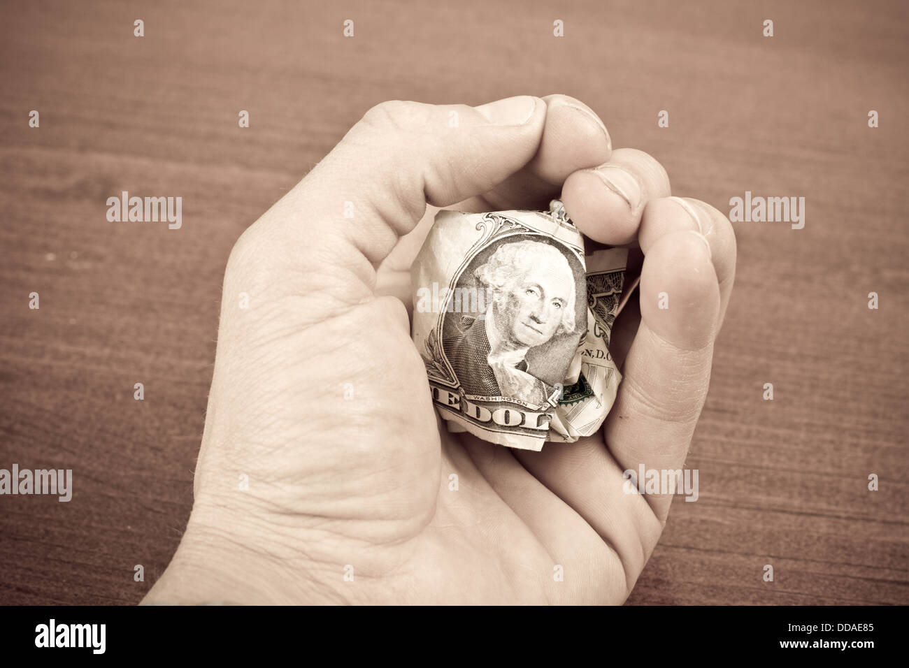 hand holding a crumbled dollar bill representing the value of money ...