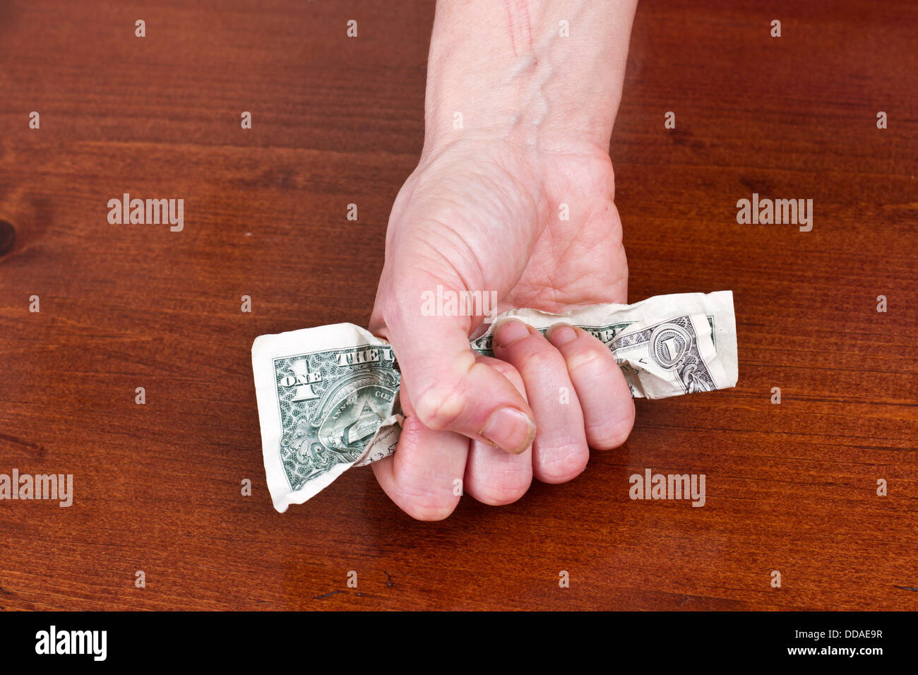 hand holding a crumbled dollar bill representing the value of money ...