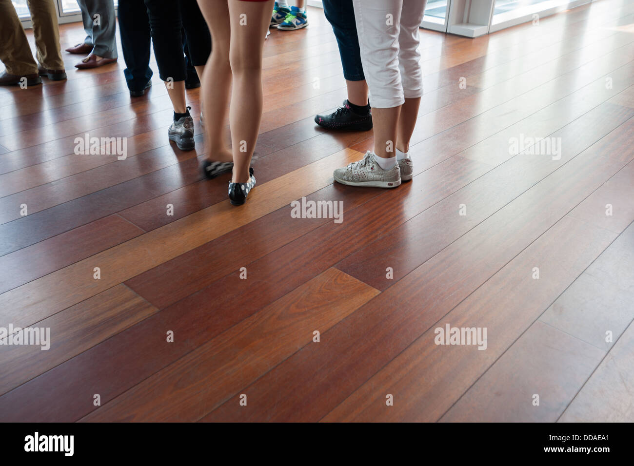 LEGS, PEOPLE STANDING AROUND AT A FUNCTION ON WOODEN FLOOR. ONLY LEGS ...