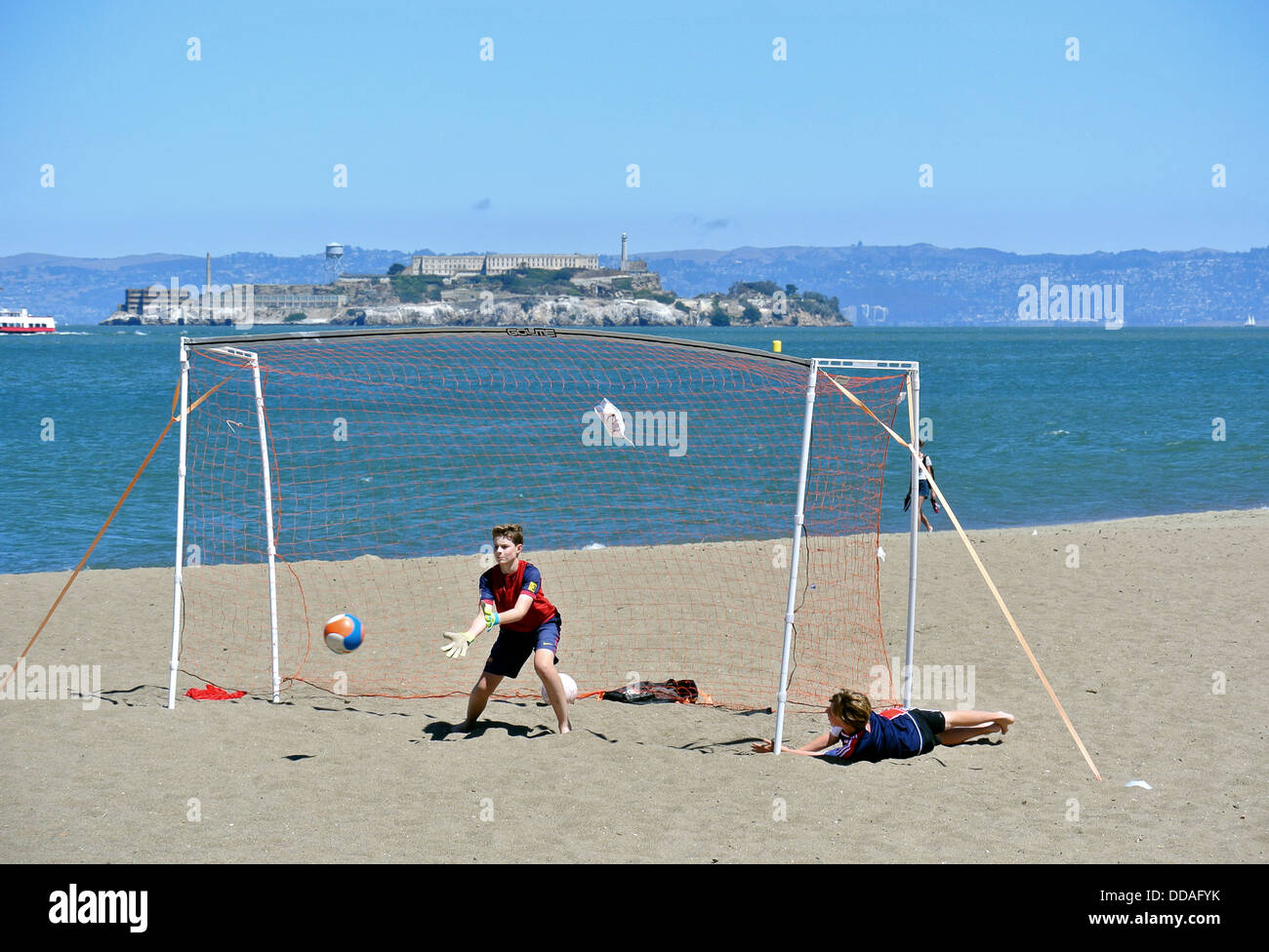 teenage boy playing soccer defending goal on the beach in the marina in ...