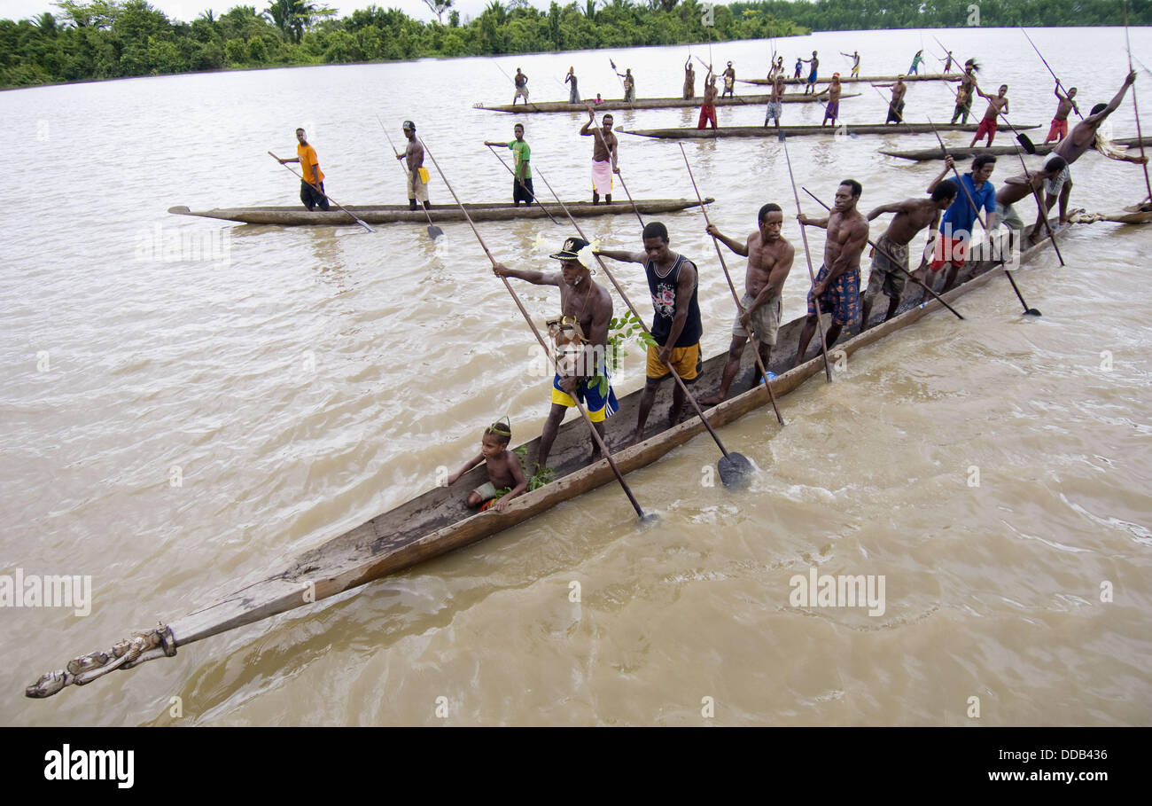 Papuan tribesmen paddling long boat, Indonesia Stock Photo - Alamy