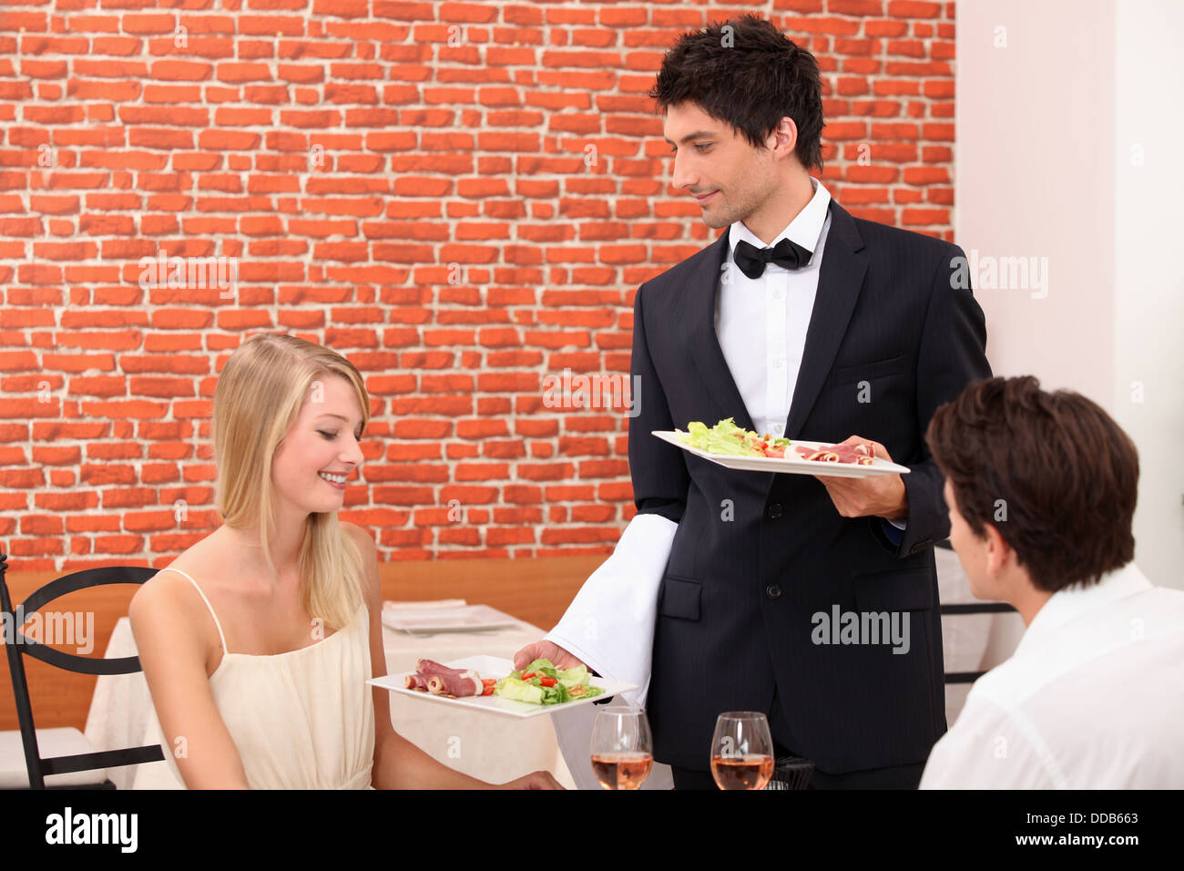 Waiter serving couple in restaurant Stock Photo - Alamy