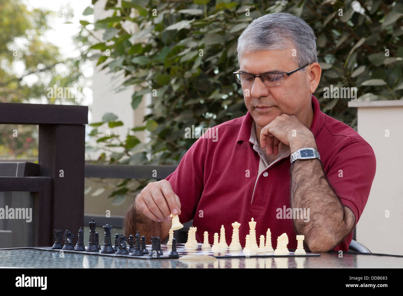 Senior man playing chess game while sitting by table Stock Photo - Alamy