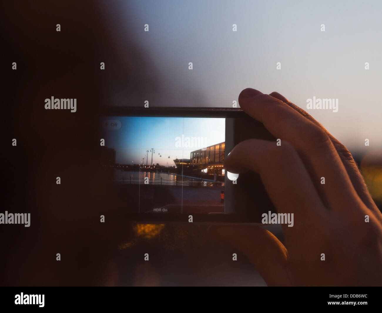Over the shoulder view at dusk of a person holding the display of a ...
