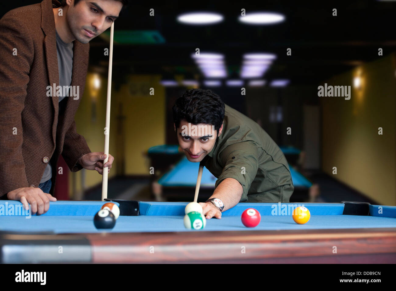 Young man playing snooker while friend standing besides Stock Photo - Alamy
