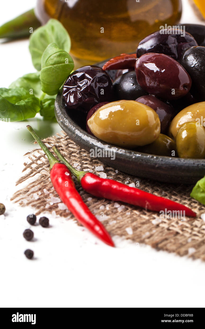 Plate of black and green olives with red hot chili peppers, basil and ...