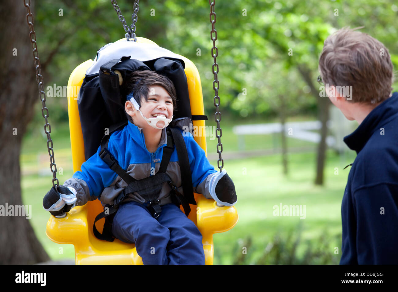Father pushing disabled son on handicap swing Stock Photo - Alamy