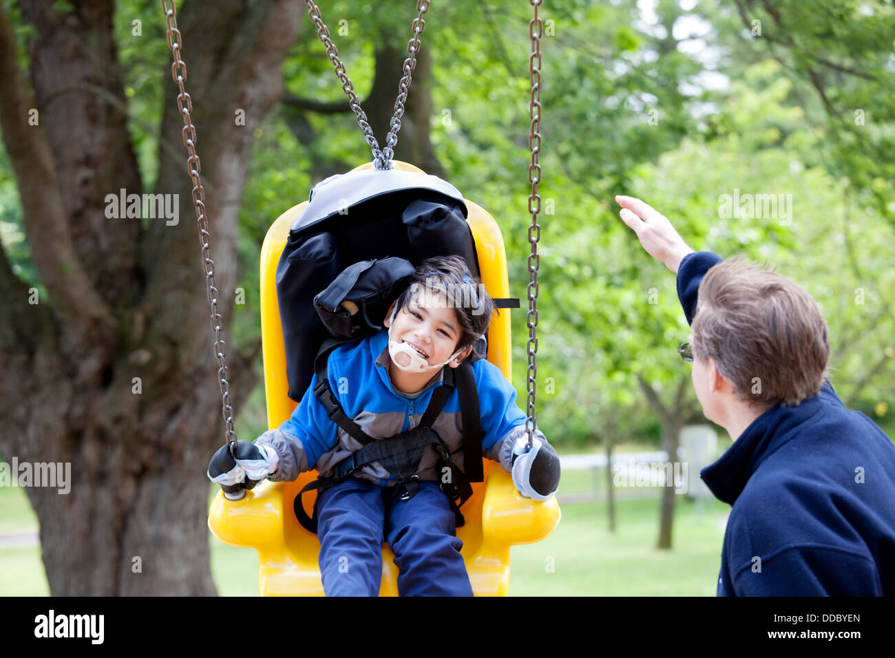 Father pushing disabled son on handicap swing Stock Photo - Alamy