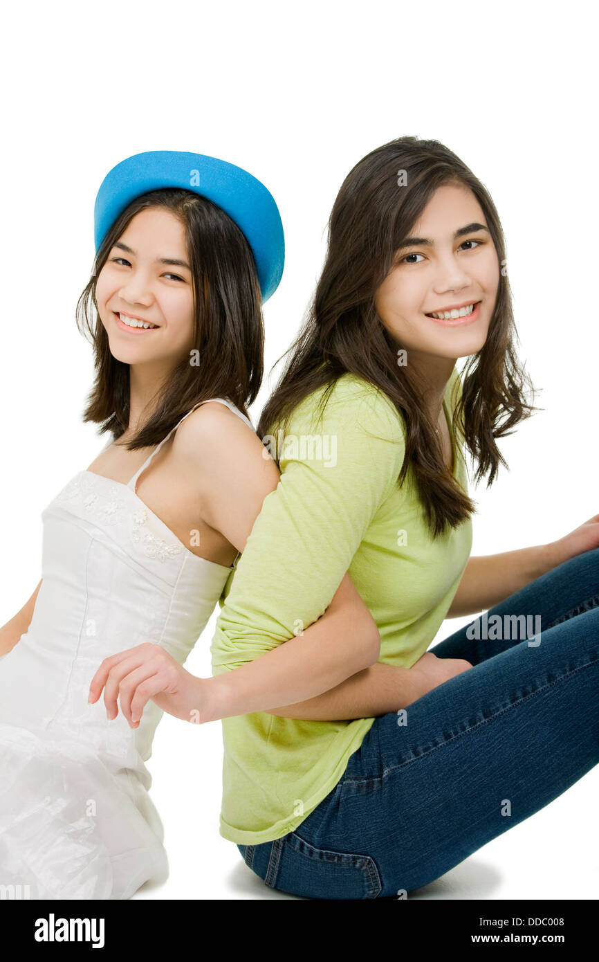 Two sisters sitting together, isolated on white Stock Photo - Alamy