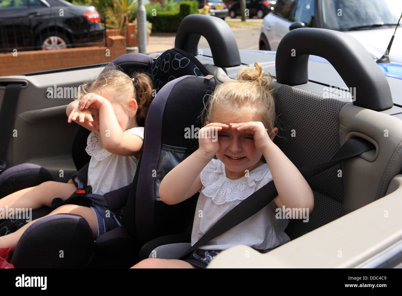 Two young girls, aged 2 and 4 shielding their eyes from the bright ...