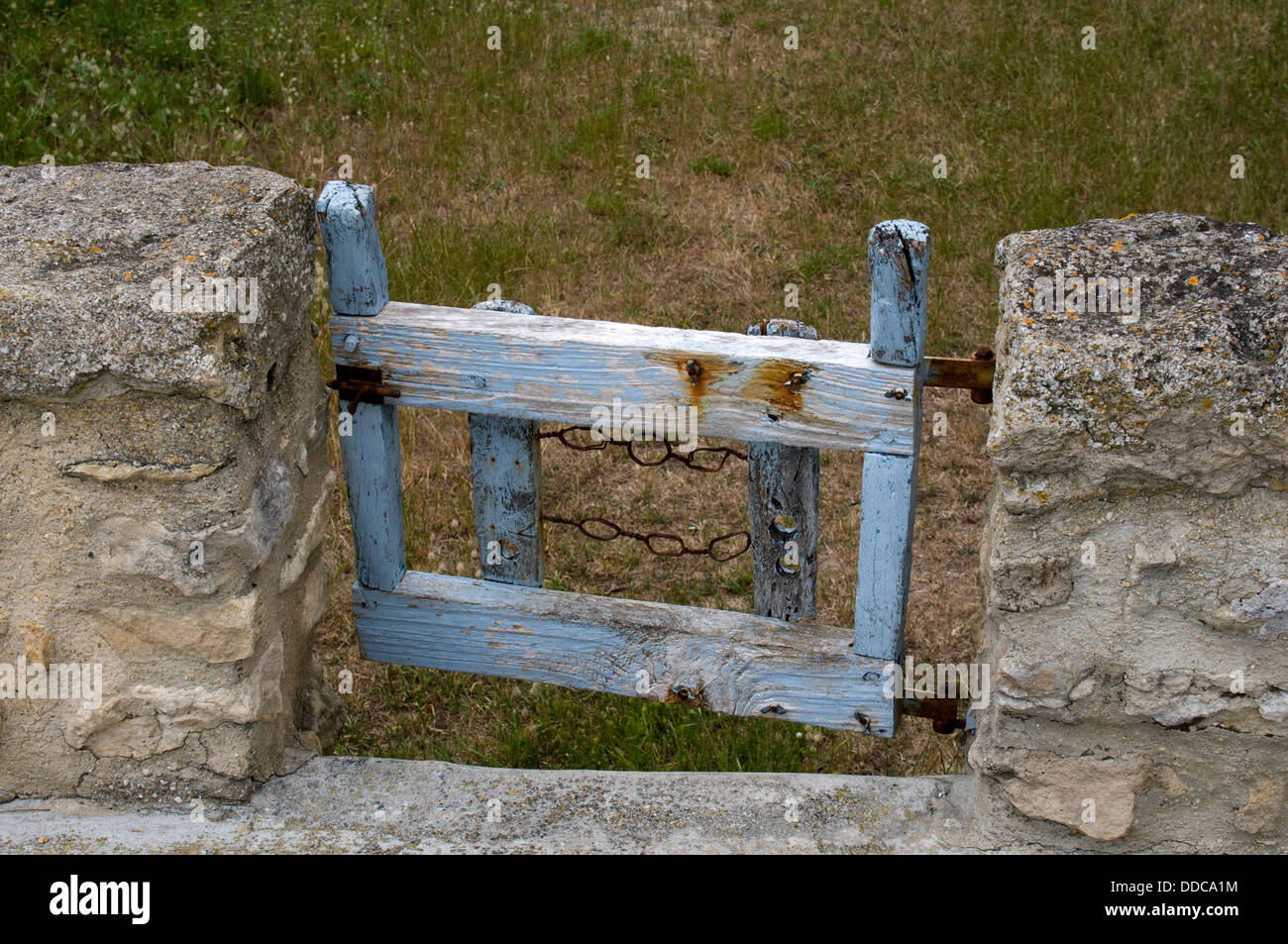 A small blue gate built into a stone wall leads into grassy garden ...