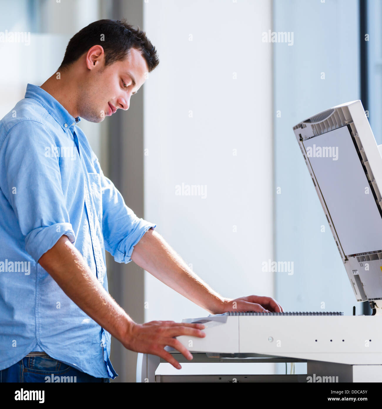 Handsome young man using a copy machine Stock Photo - Alamy