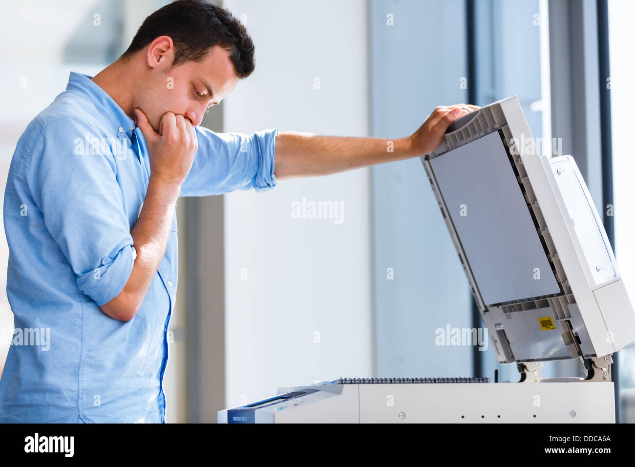 Handsome young man using a copy machine Stock Photo - Alamy