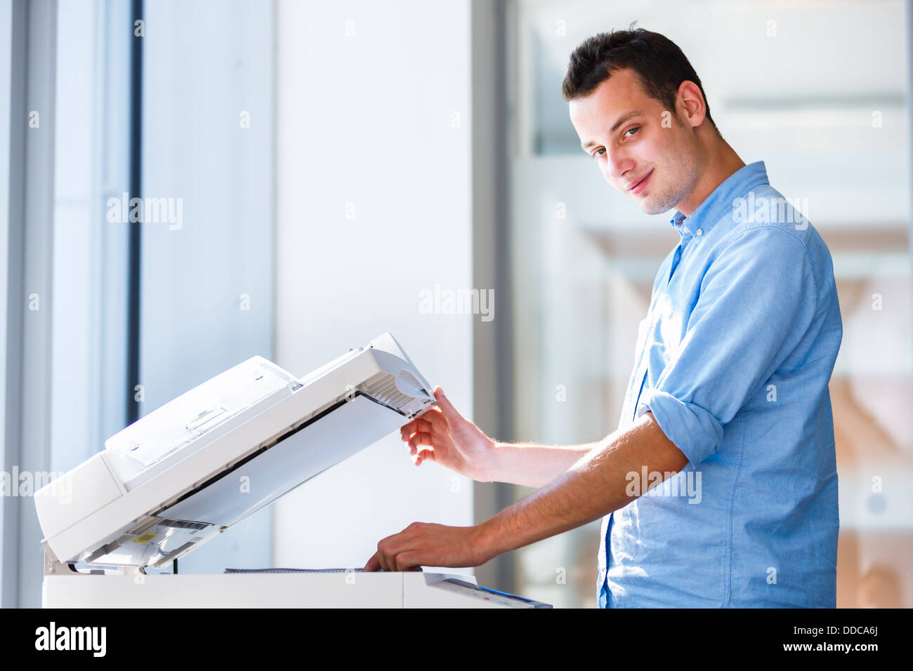 Handsome young man using a copy machine Stock Photo - Alamy