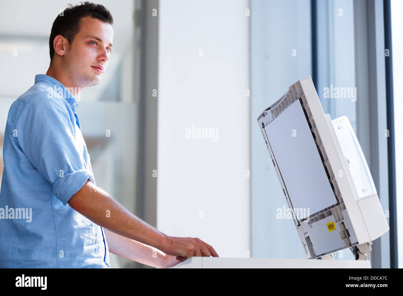 Handsome young man using a copy machine Stock Photo - Alamy