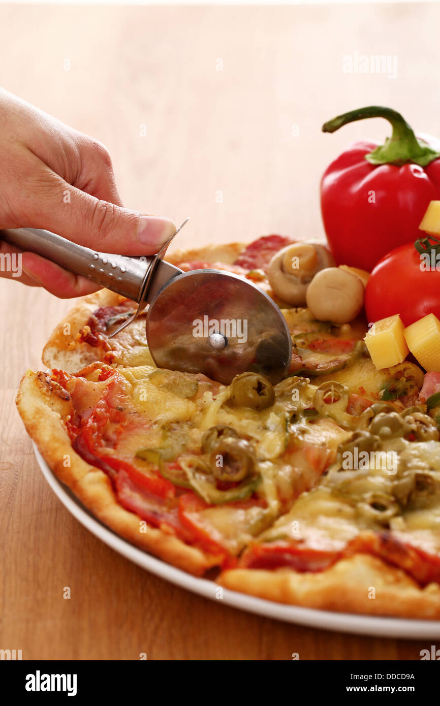 Fresh italian pizza in plate being sliced Stock Photo - Alamy