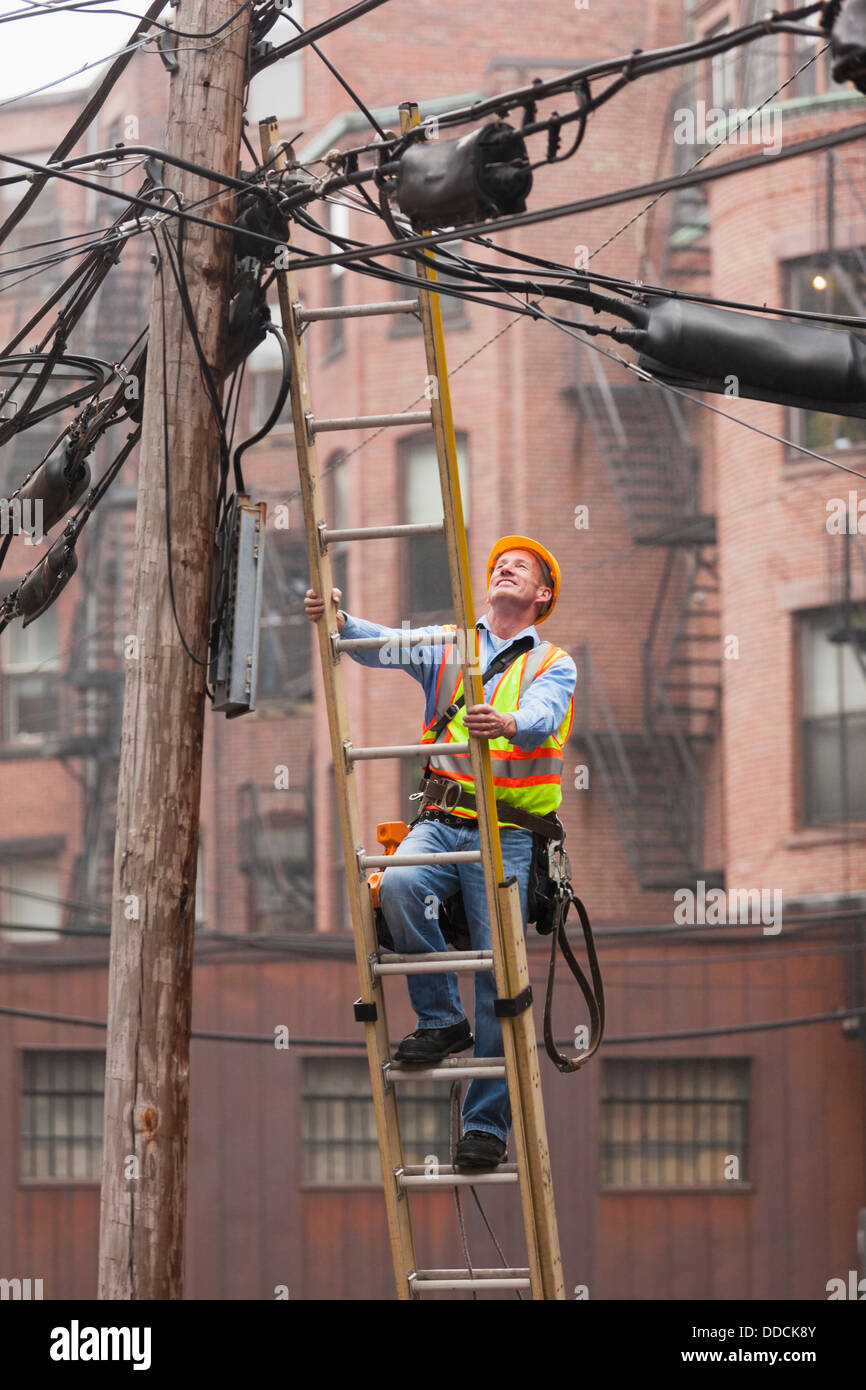Cable lineman climbing up a ladder on city power pole Stock Photo - Alamy