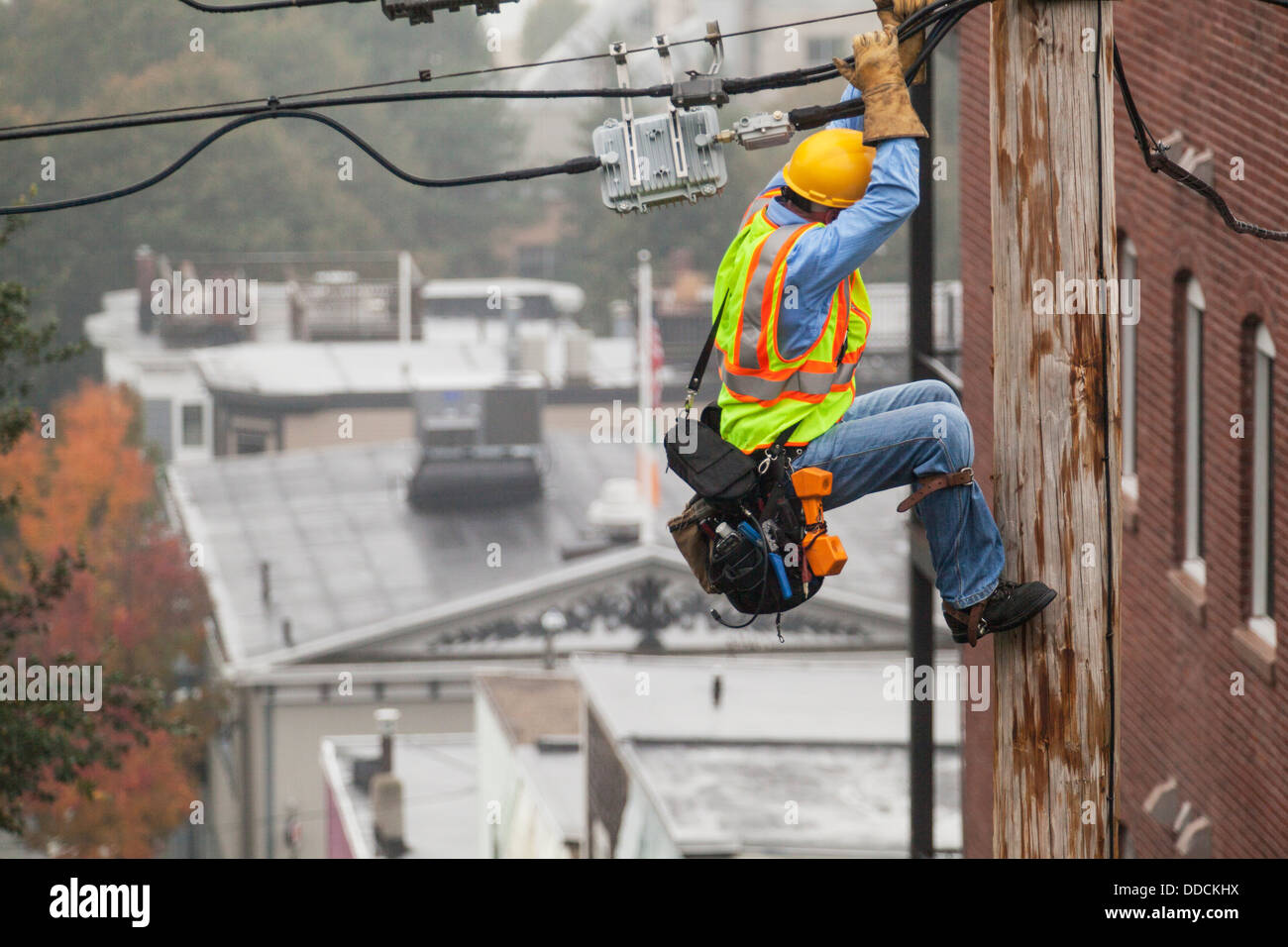 Cable lineman holding onto pole while using lineman spikes to adjust ...