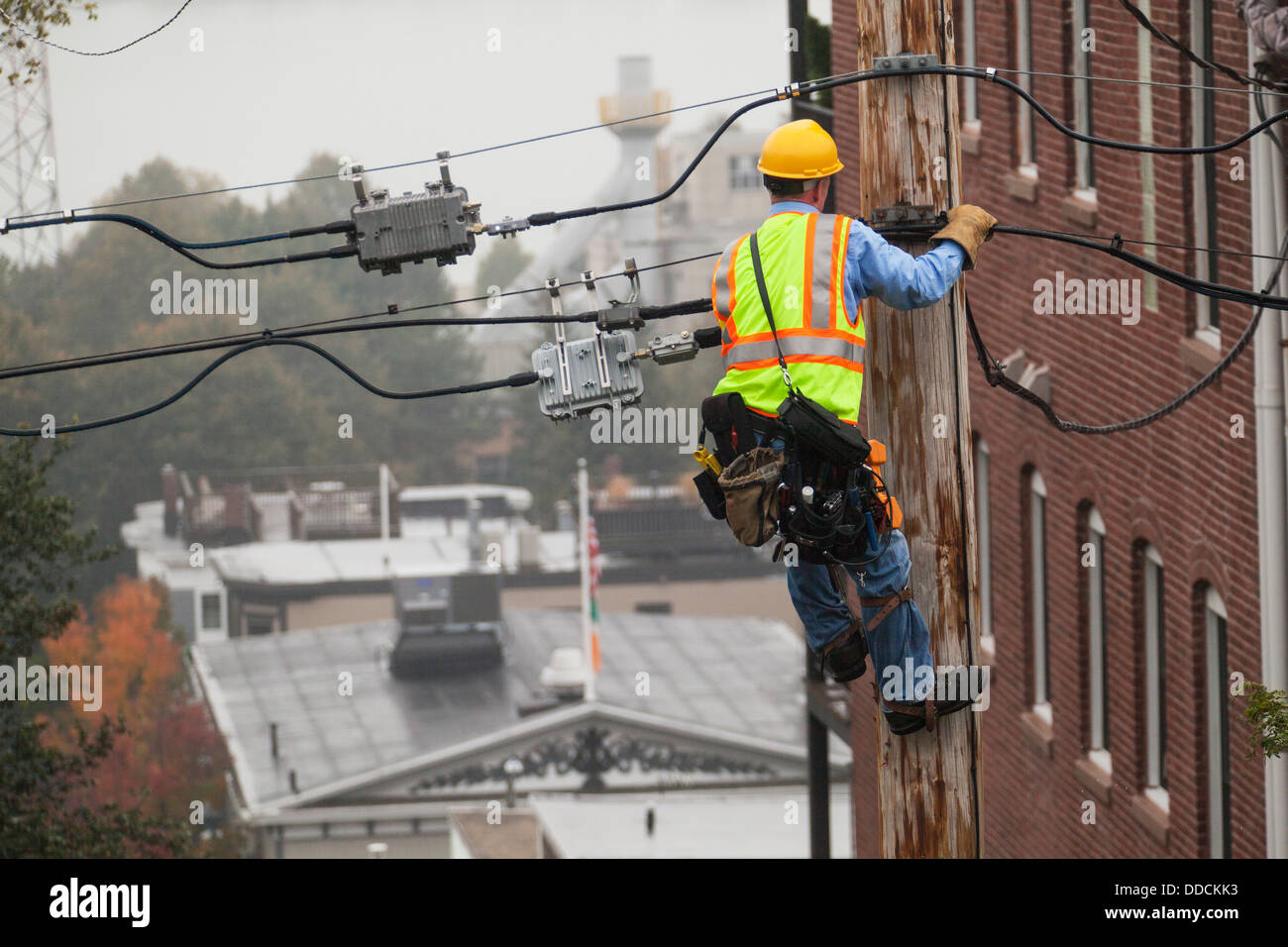 Cable lineman using lineman spikes to climb down pole Stock Photo - Alamy