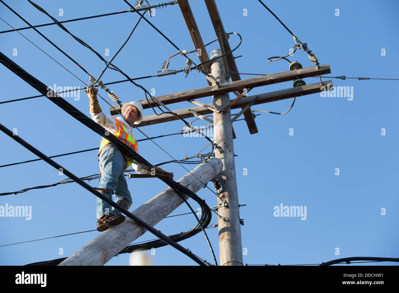 Cable lineman installing new suspension wire from power pole brace ...