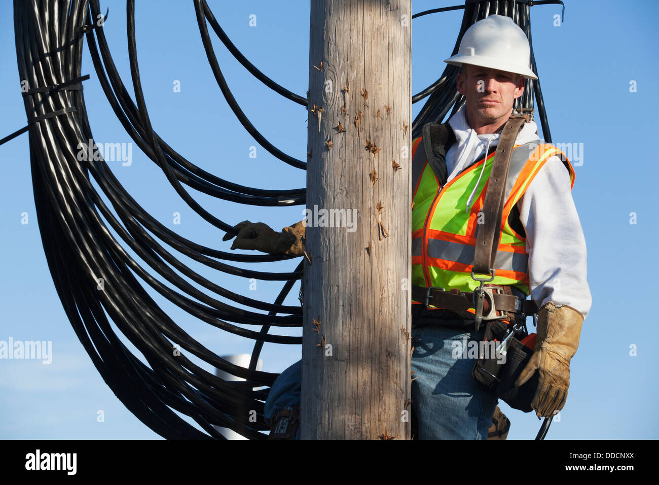Cable lineman on a power pole with new bundle of cable Stock Photo - Alamy