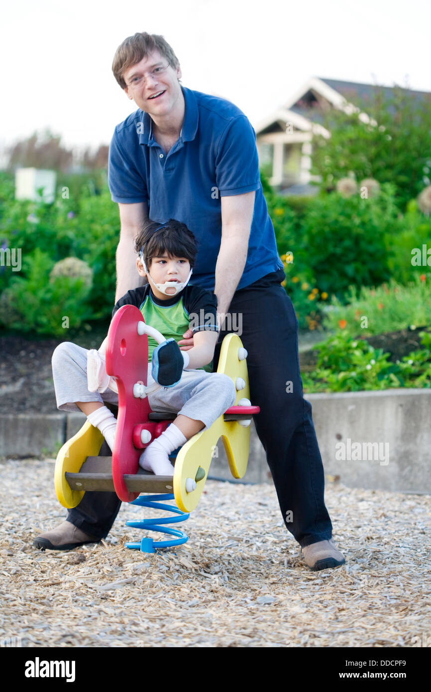 Father helping disabled son play at playground Stock Photo - Alamy