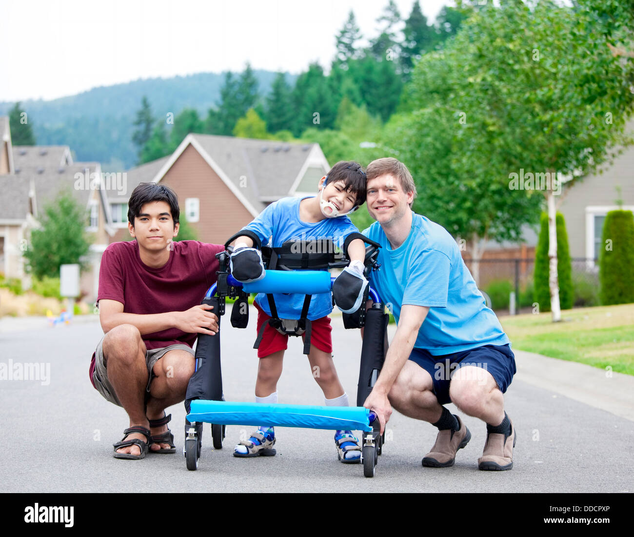 Disabled boy in walker surrounded by father and older brother Stock ...