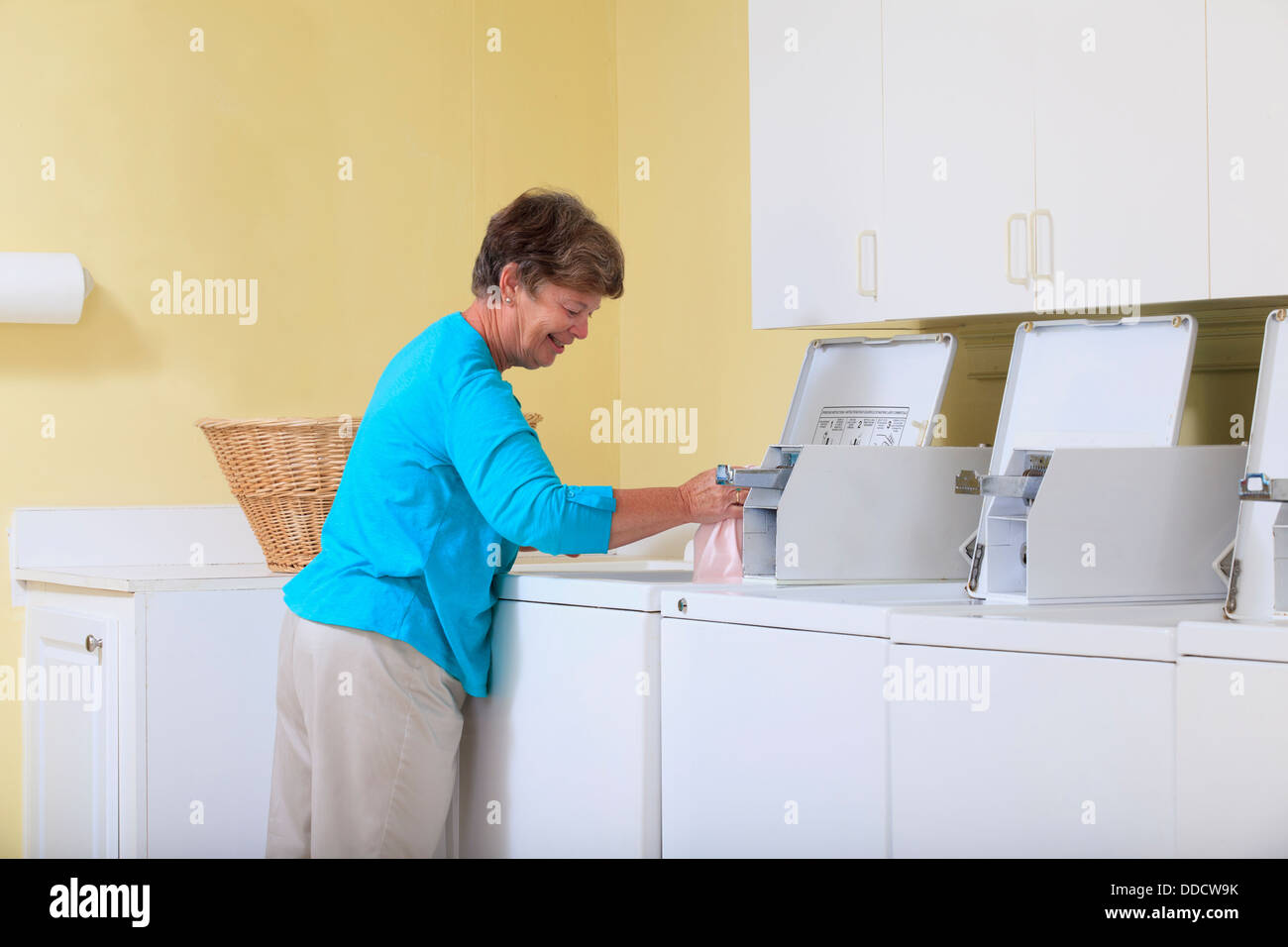 Senior woman putting laundry in a washing machine Stock Photo - Alamy